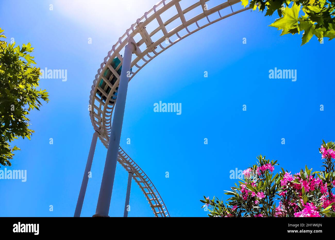 Abstract rollercoaster ride against blue sky and flowers Stock Photo ...