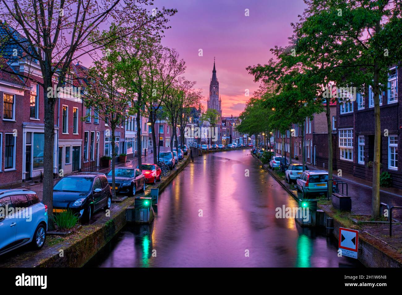 Canal with parked along cars in Delft town in evening dusk after rain ...