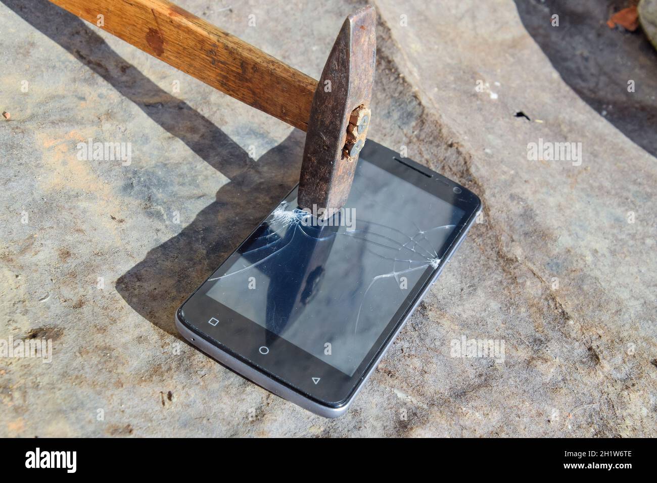 Hammer and smartphone. The screen of the smartphone, a broken hammer ...