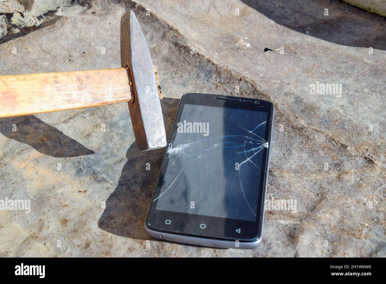 Hammer and smartphone. The screen of the smartphone, a broken hammer ...