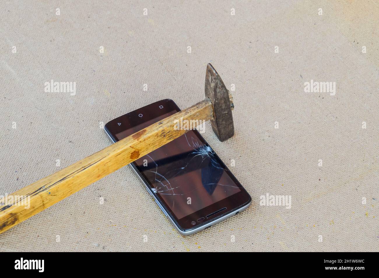 Hammer and smartphone. The screen of the smartphone, a broken hammer ...