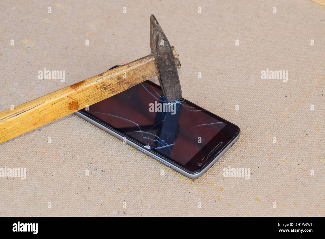 Hammer and smartphone. The screen of the smartphone, a broken hammer ...