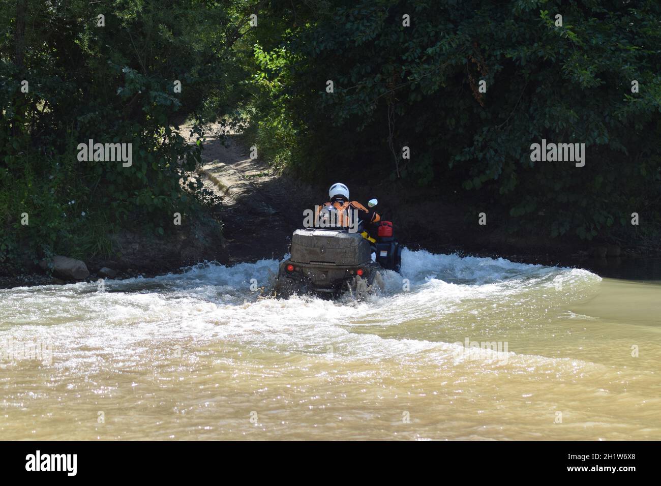 The man on the ATV crosses a stream. Tourist walks on a cross-country ...