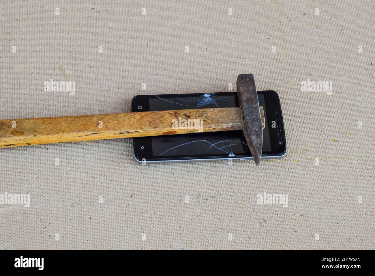 Hammer and smartphone. The screen of the smartphone, a broken hammer ...