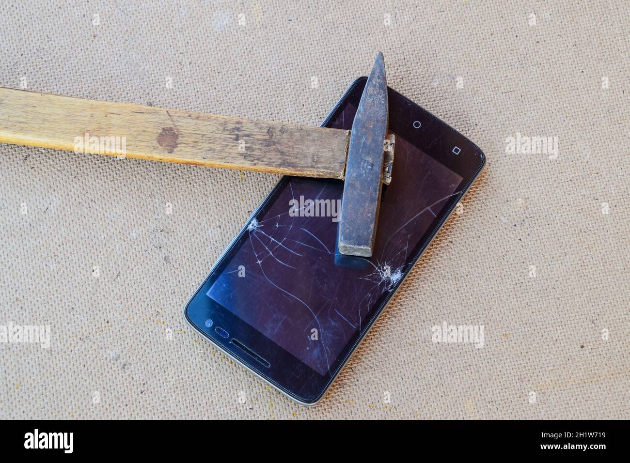 Hammer and smartphone. The screen of the smartphone, a broken hammer ...