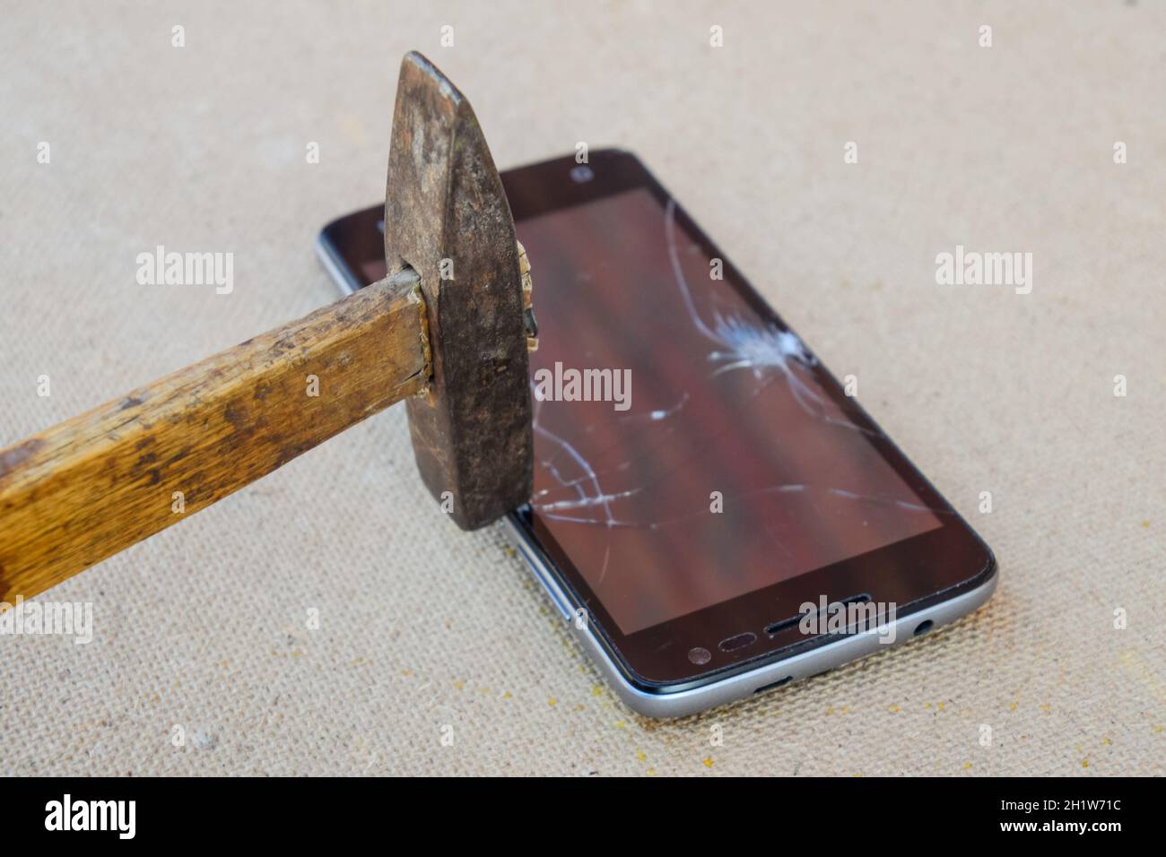 Hammer and smartphone. The screen of the smartphone, a broken hammer ...