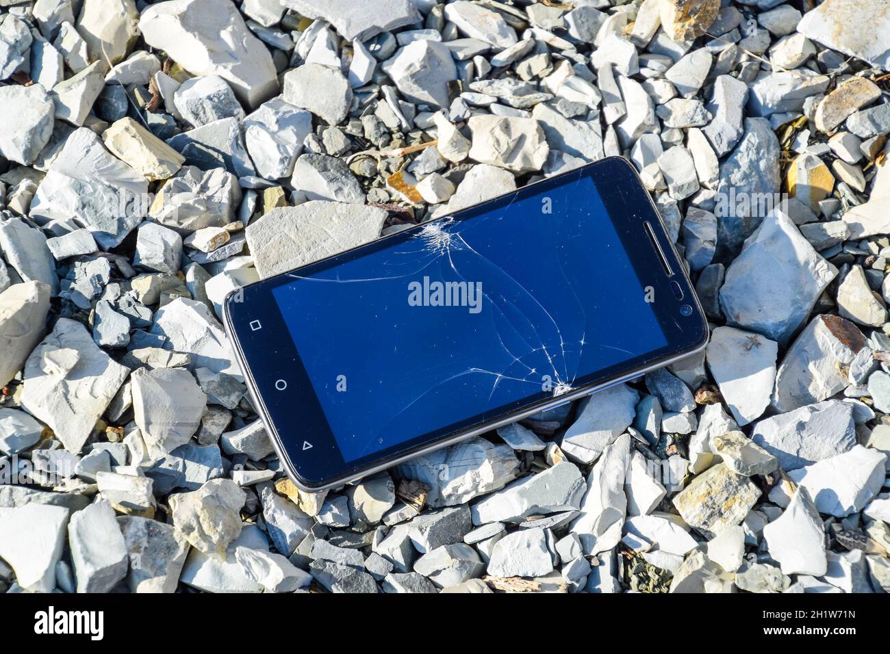 Frustrated phone on the rocks. Glass shattered on rocks on a smartphone ...