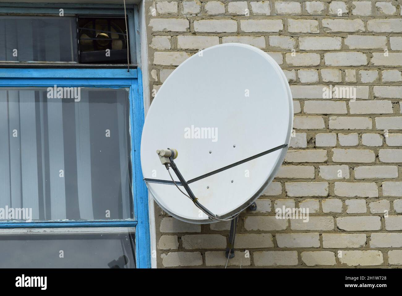 Satellite antenna on the wall near the window. Satellite television ...
