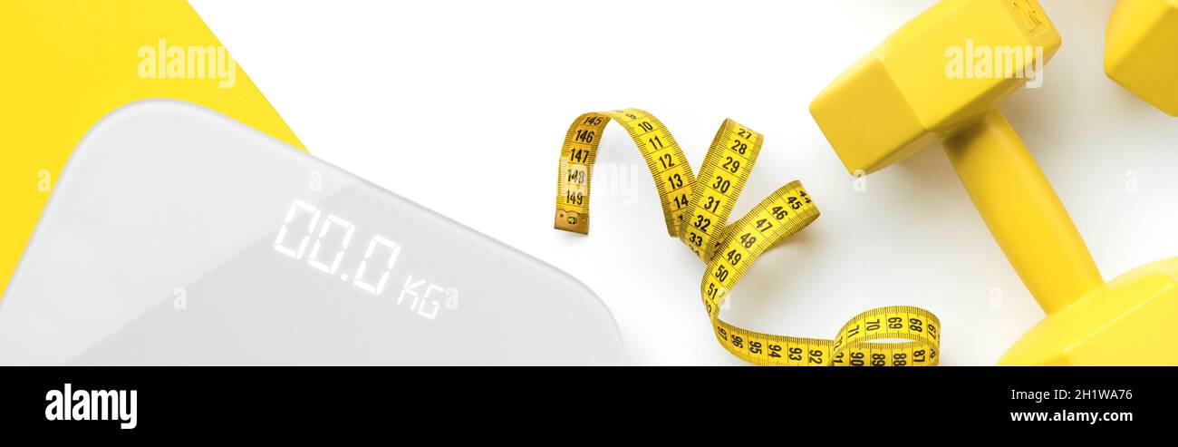 Flat lay top view scales, dumbbell and tape measure on white yellow ...