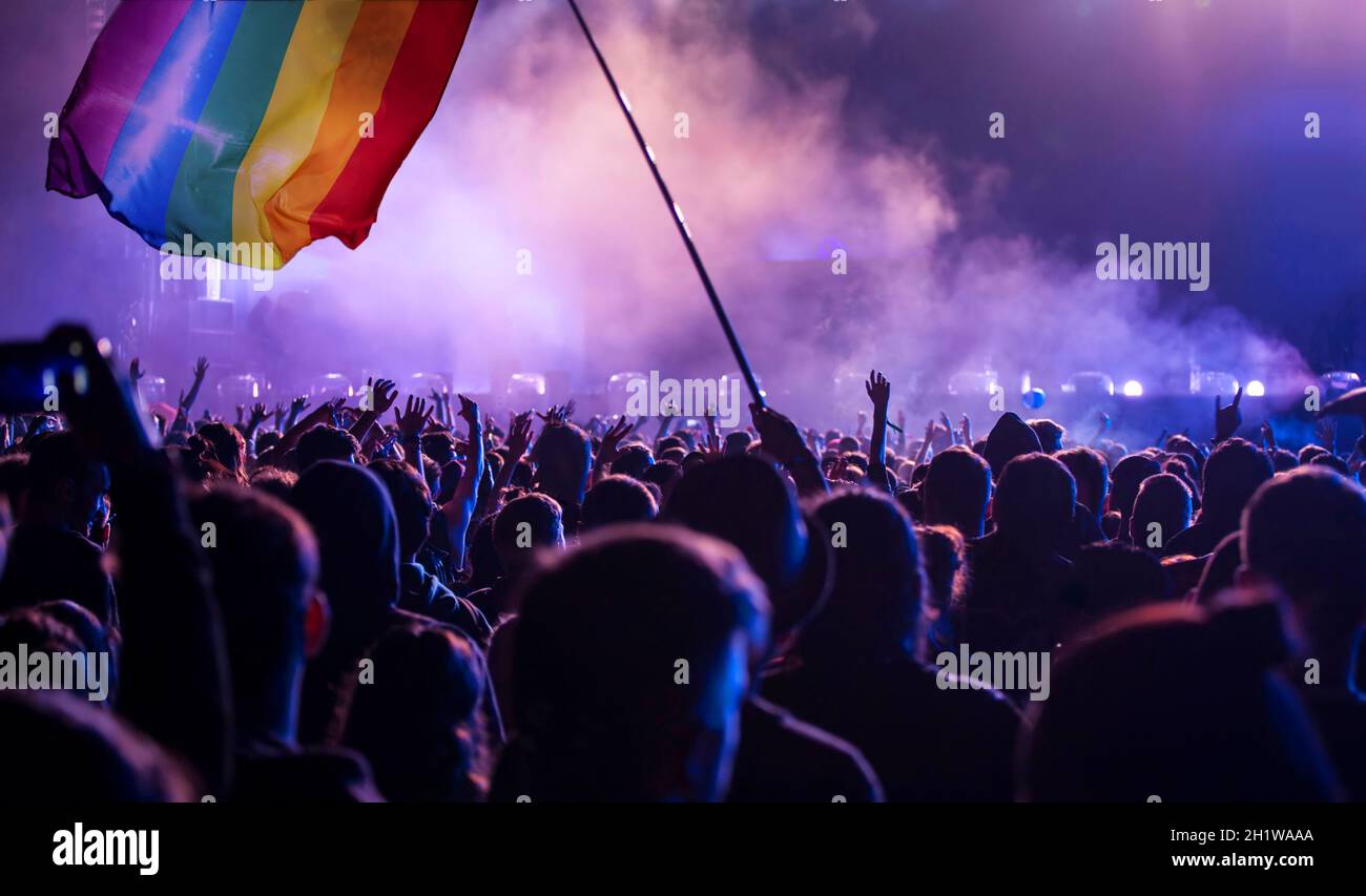 Pride community at a parade with hands raised and the LGBT flag ...