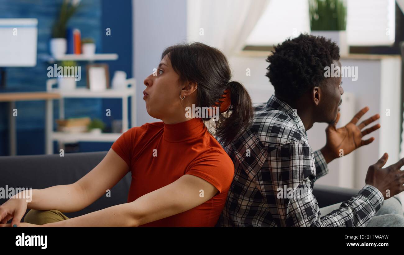 Irritated Interracial Couple Getting Into Argument On Sofa At Home