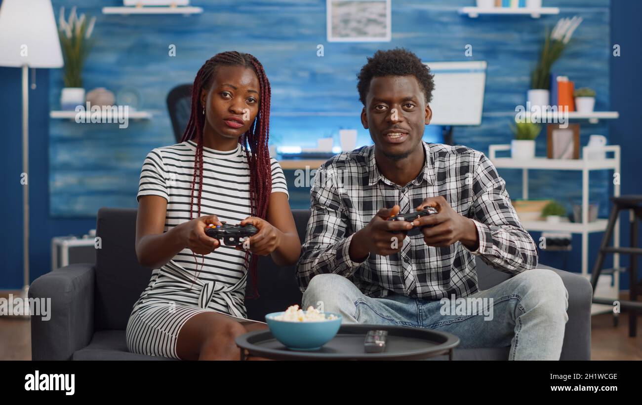 African american couple losing video game match on living room couch ...