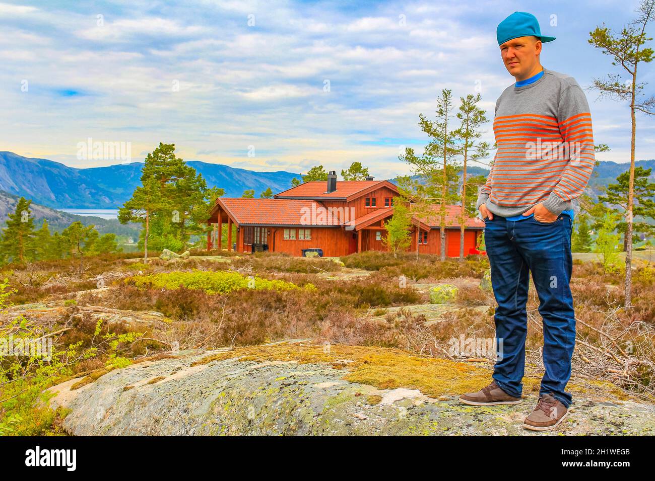 Young hiker is watching the landscape of norwegian mountains cottages ...
