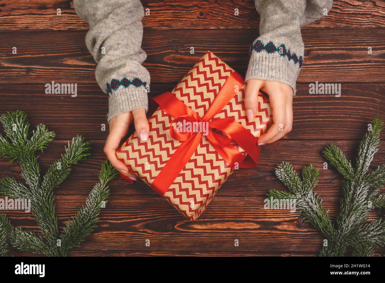 Woman holding wrapped Christmas present in her hands, view from above ...