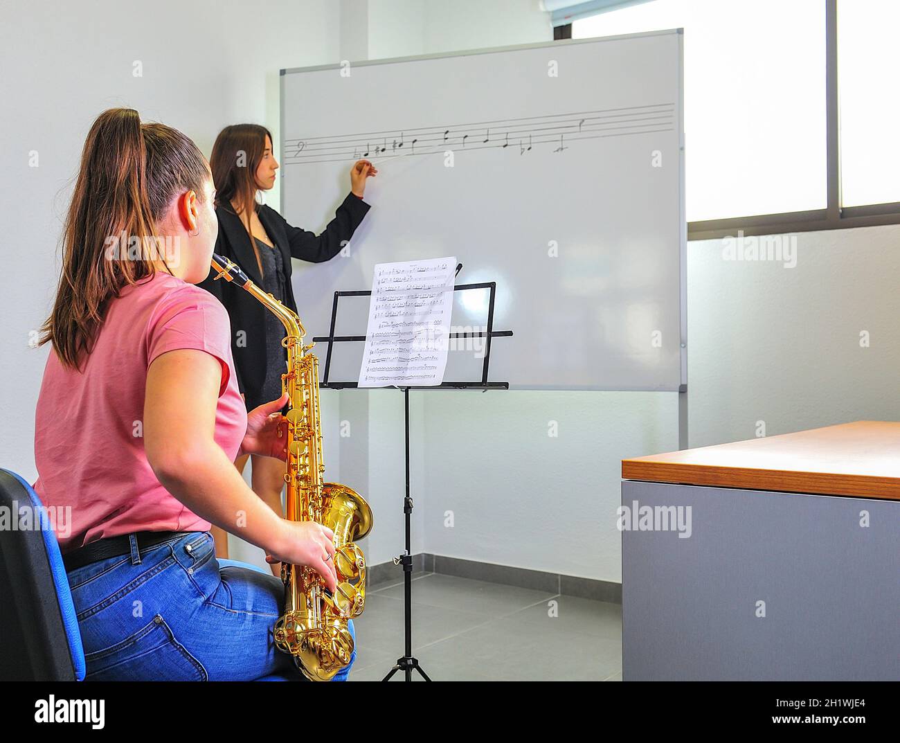 Teacher corrects music in the classroom, to a young student Stock Photo ...