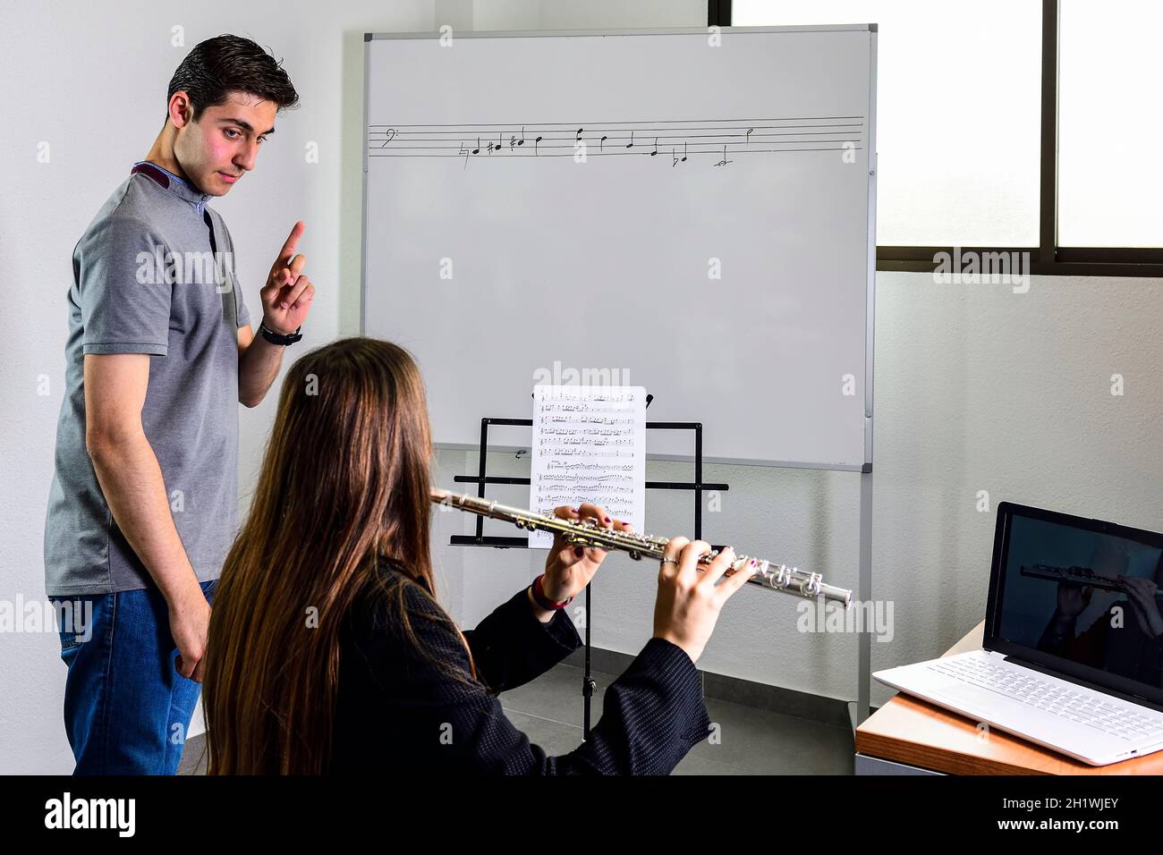Teacher corrects music in the classroom, to a young student Stock Photo ...