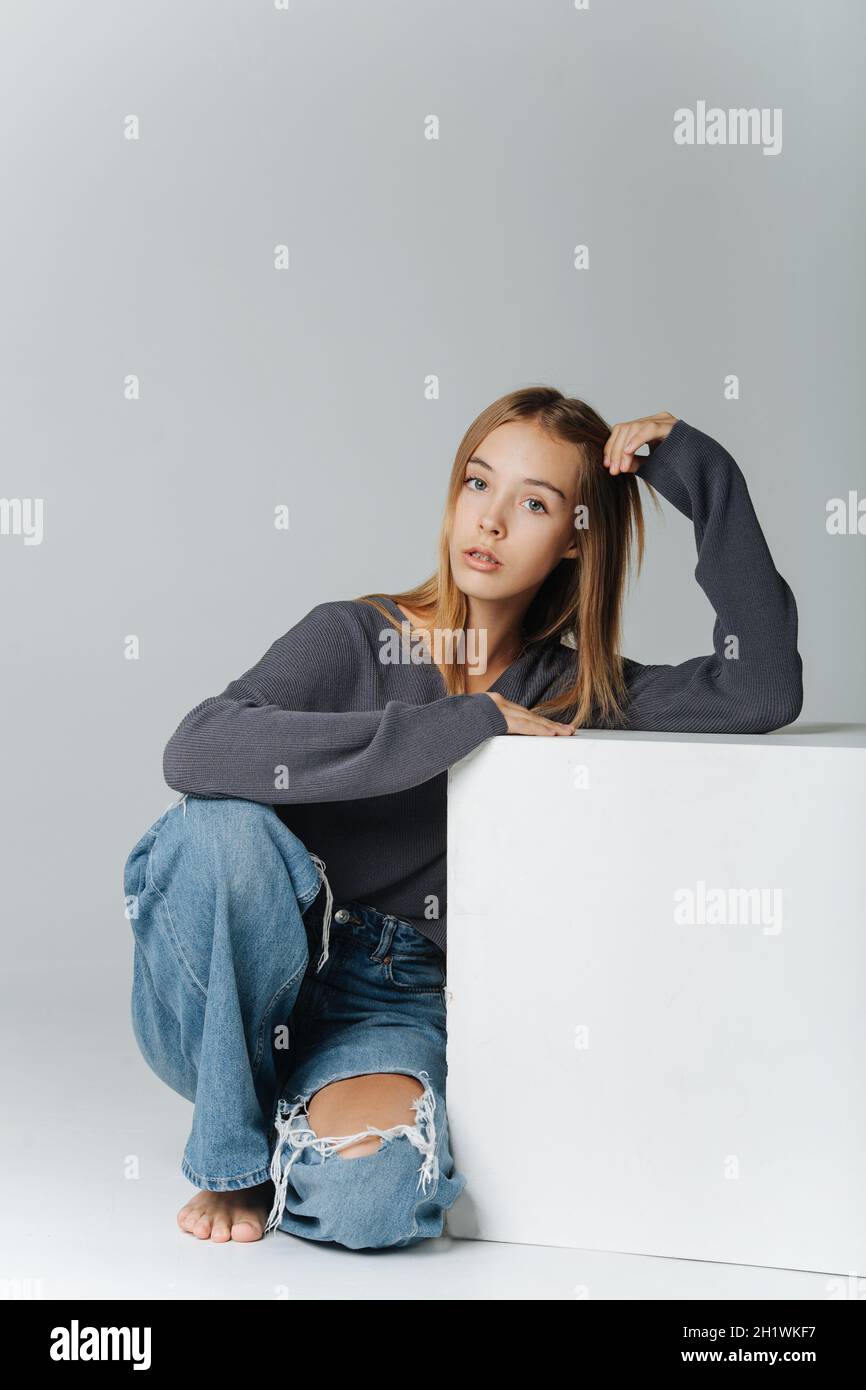 Portrait of a sensual teenage girl sitting on one leg, leaning on a ...