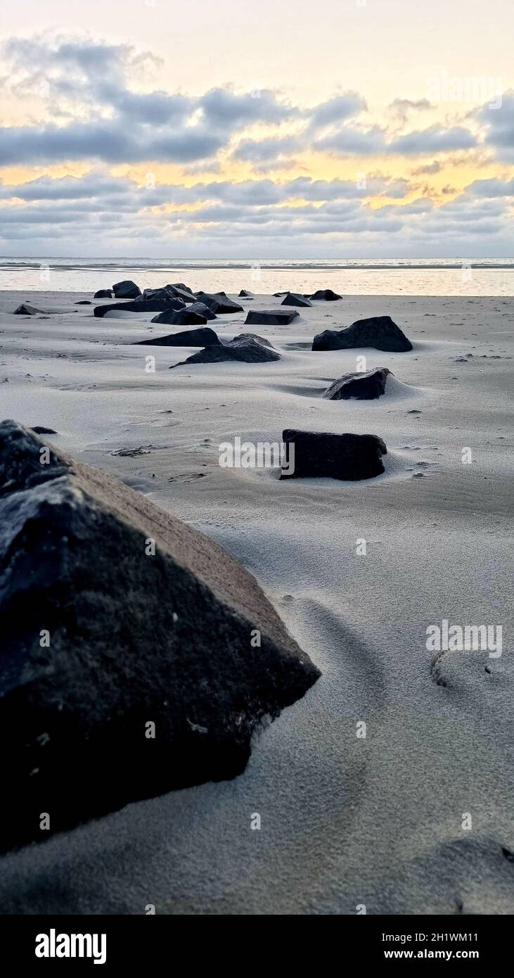 Rocks on the beach sand at sunr Stock Photo - Alamy