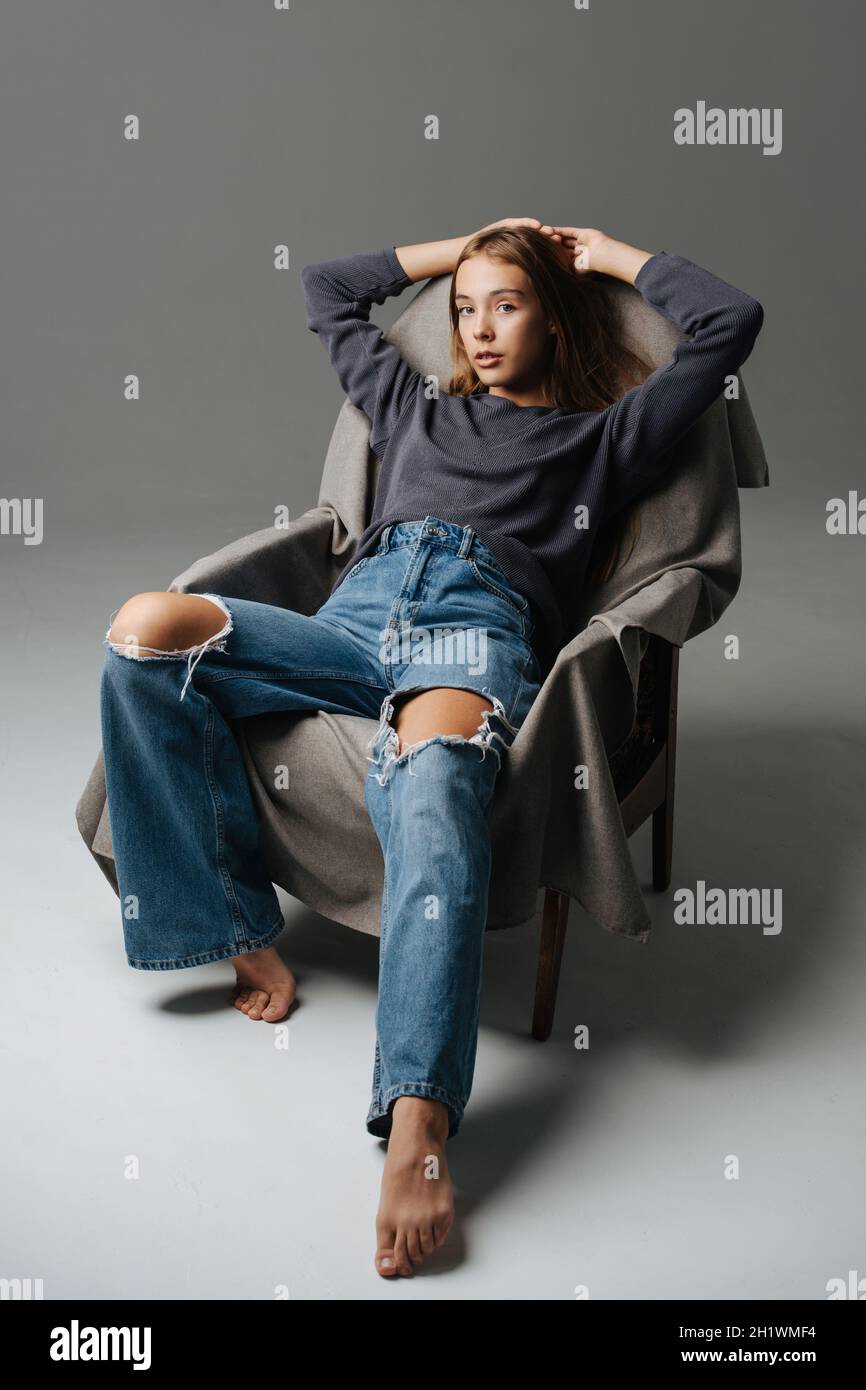 Chill teenage girl sitting on an armchair, holding hands over her head ...