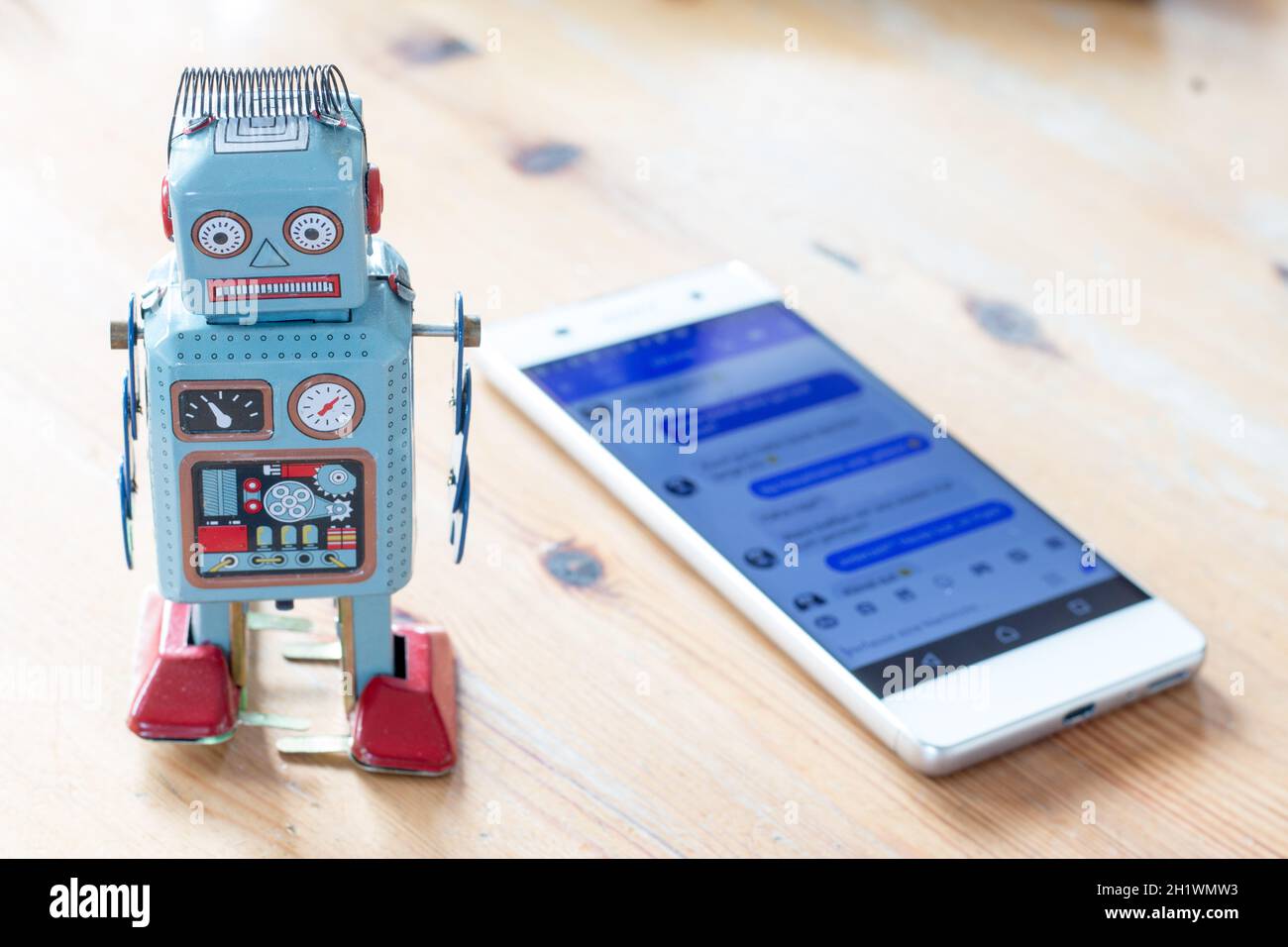 Toy robot and smartphone, symbol for chatbot and messenger Stock Photo ...
