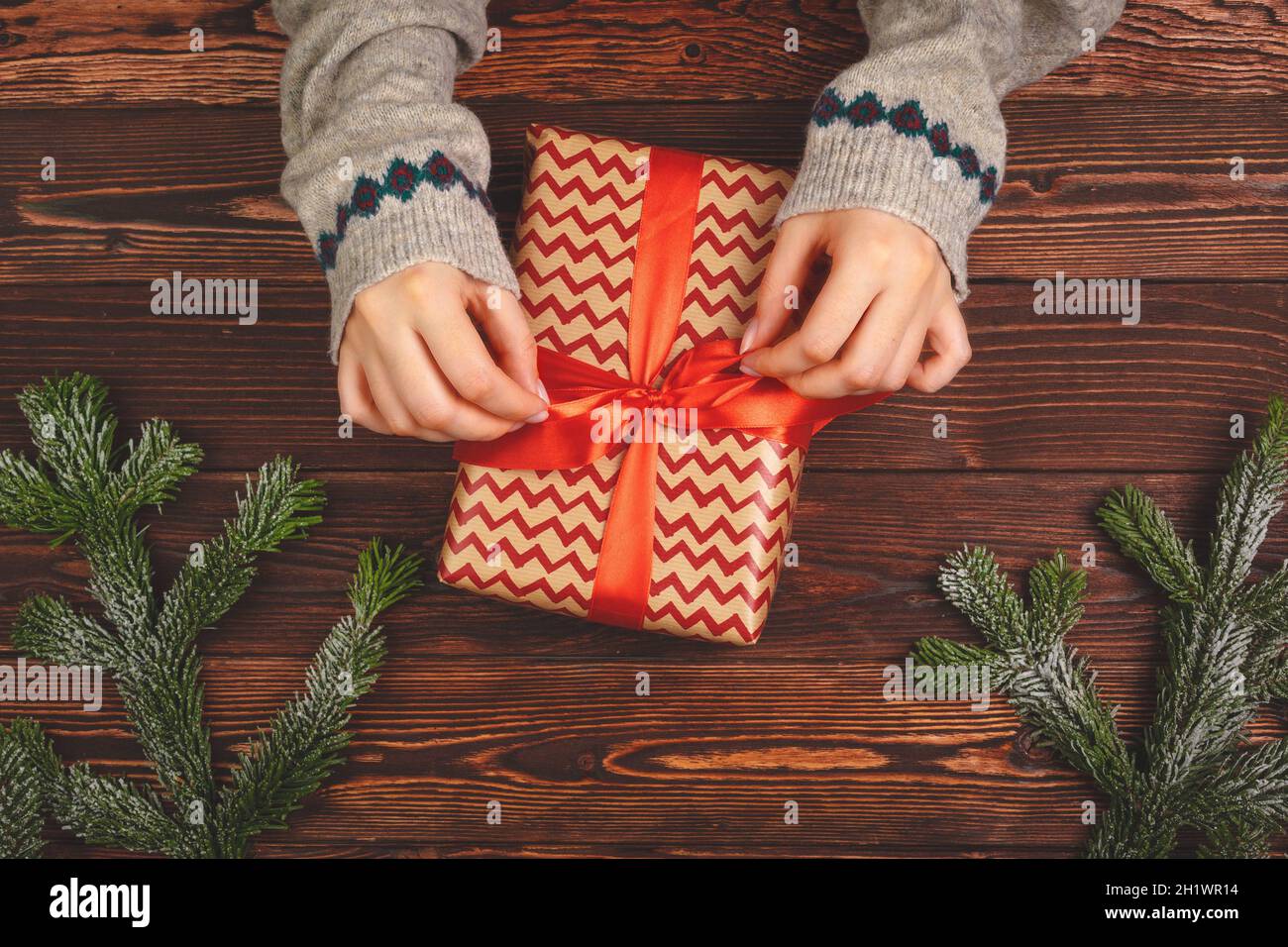 Woman holding wrapped Christmas present in her hands, view from above ...