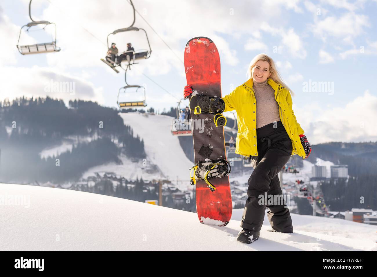 Young woman with snowboard on the slope of hill at winter resort Stock ...