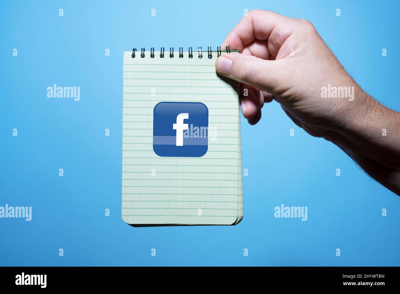 a notepad with the Facebook symbol in the hand of a man with the blue ...
