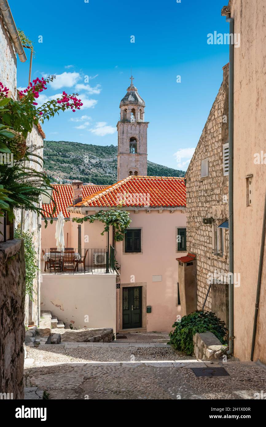 Clock tower behind traditional houses in alley with stairs in Dubrovnik ...