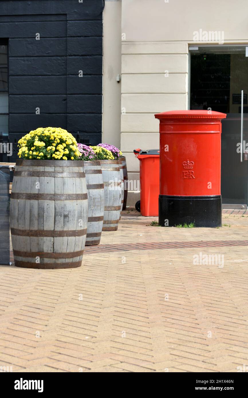 close up of a red mail pillar box with a red recycling bin in the ...