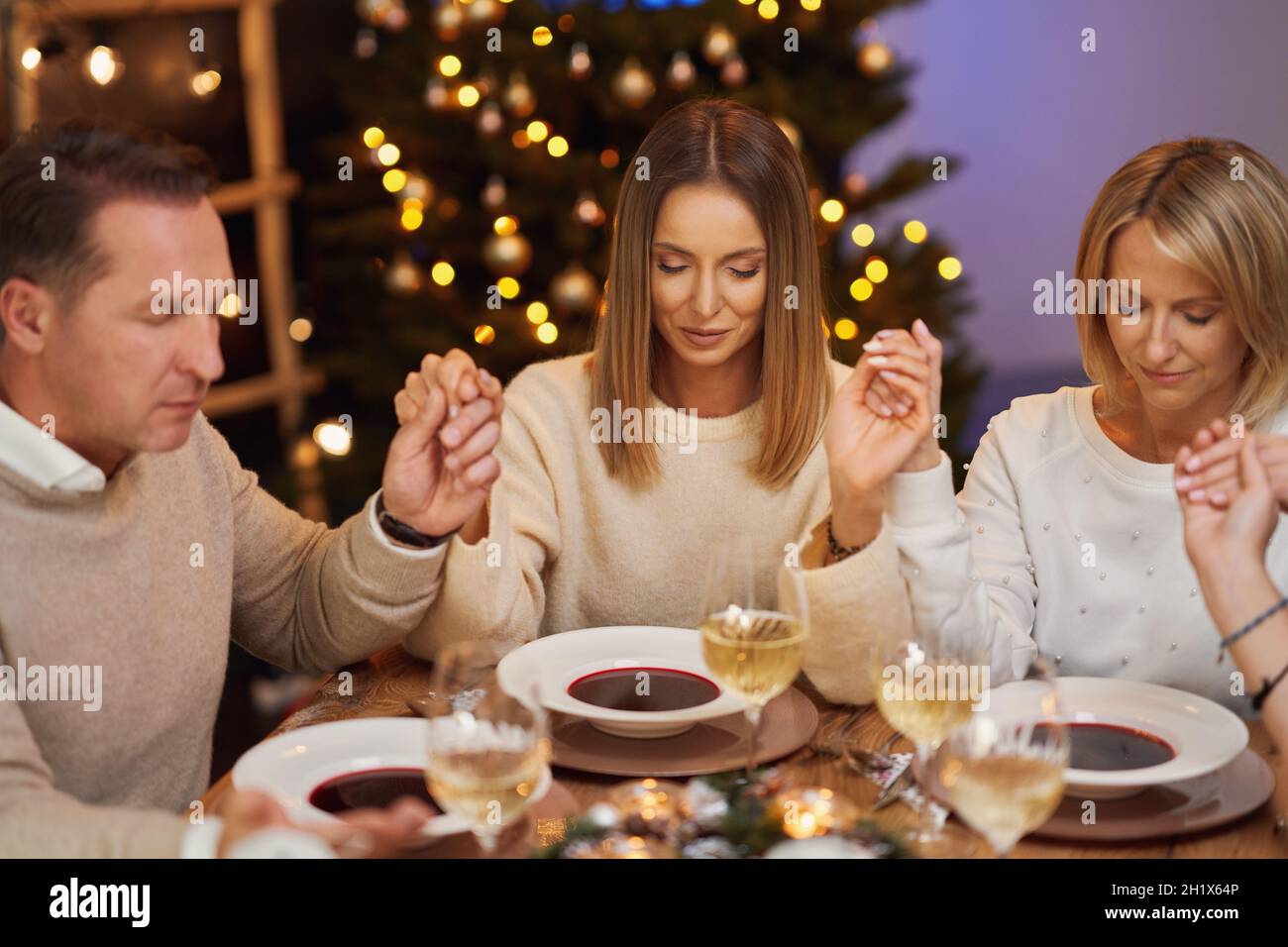 Friends praying before christmas dinner Stock Photo - Alamy