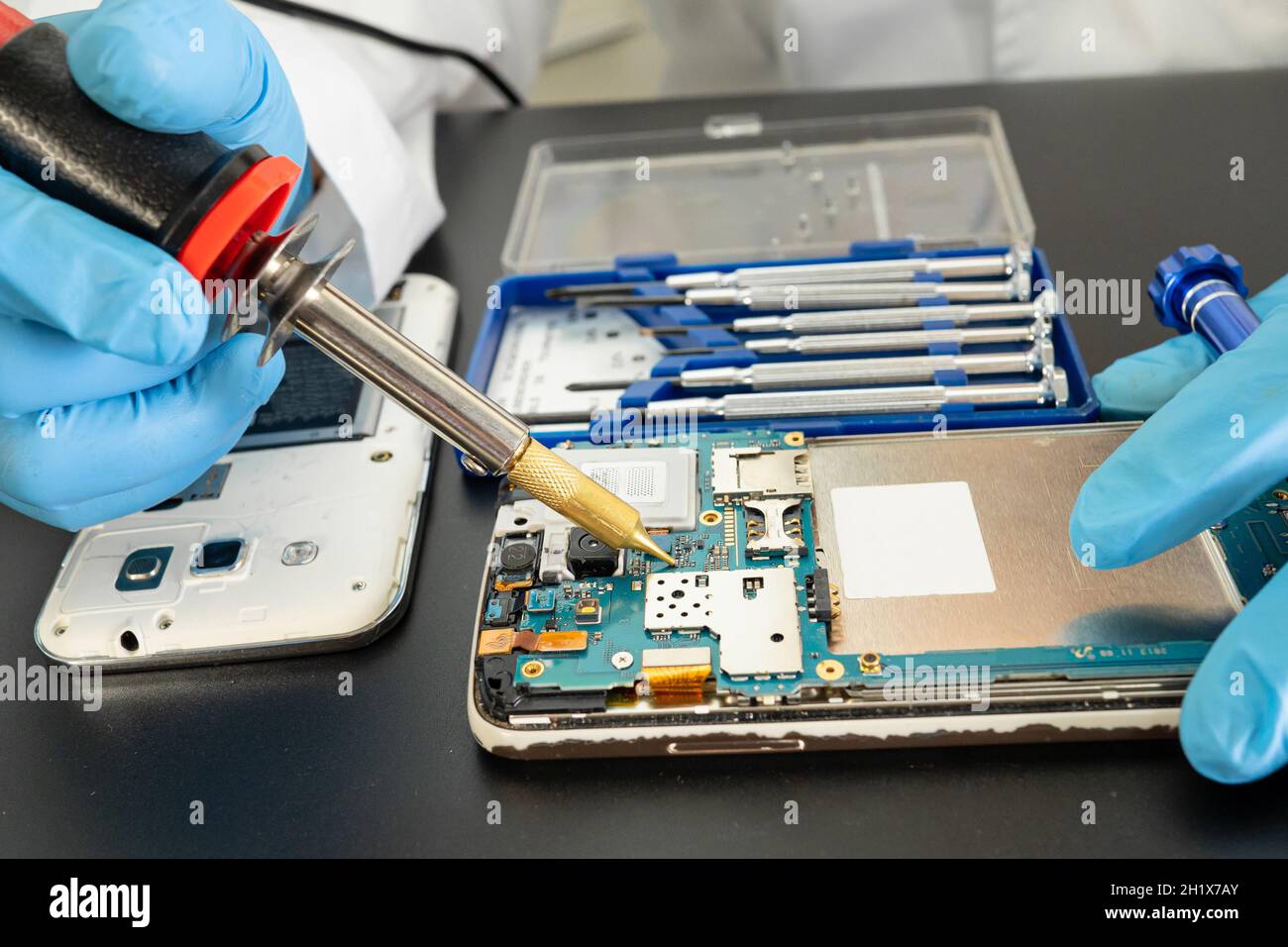 Technician repairing inside of mobile phone by soldering iron ...