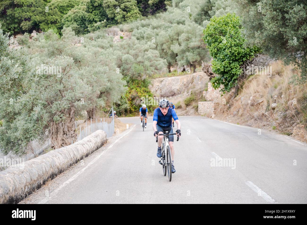 Senior cyclist with two unrecognisable cyclists in the background on a ...