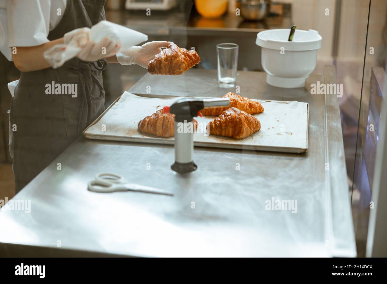 Professional confectioner holds cream and crusty croissant standing at ...