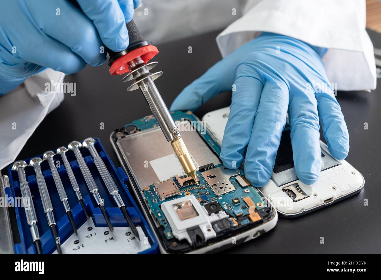 Technician repairing inside of mobile phone by soldering iron ...