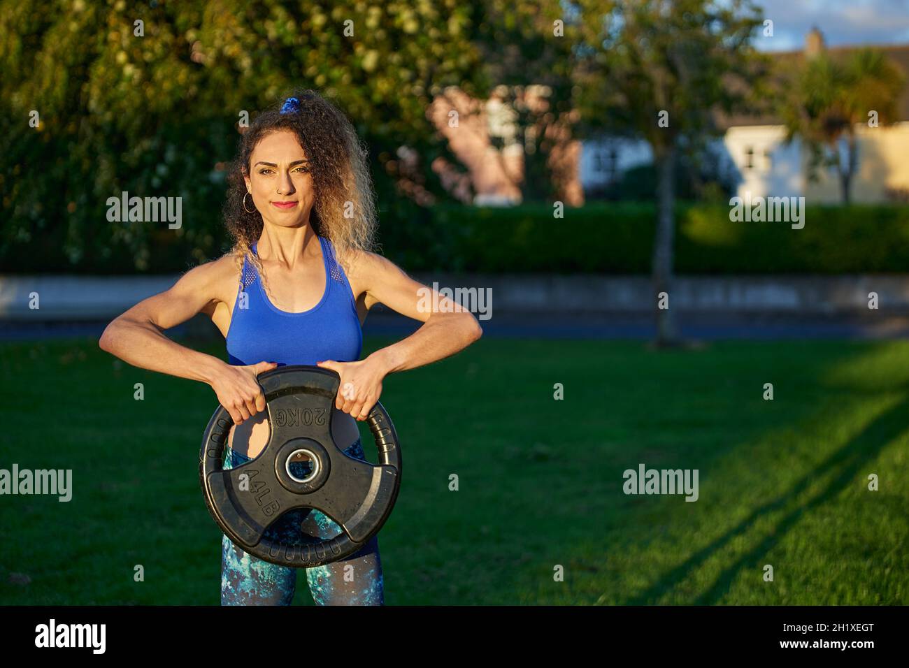 atletica woman in good physical shape lifting a very heavy disc while ...