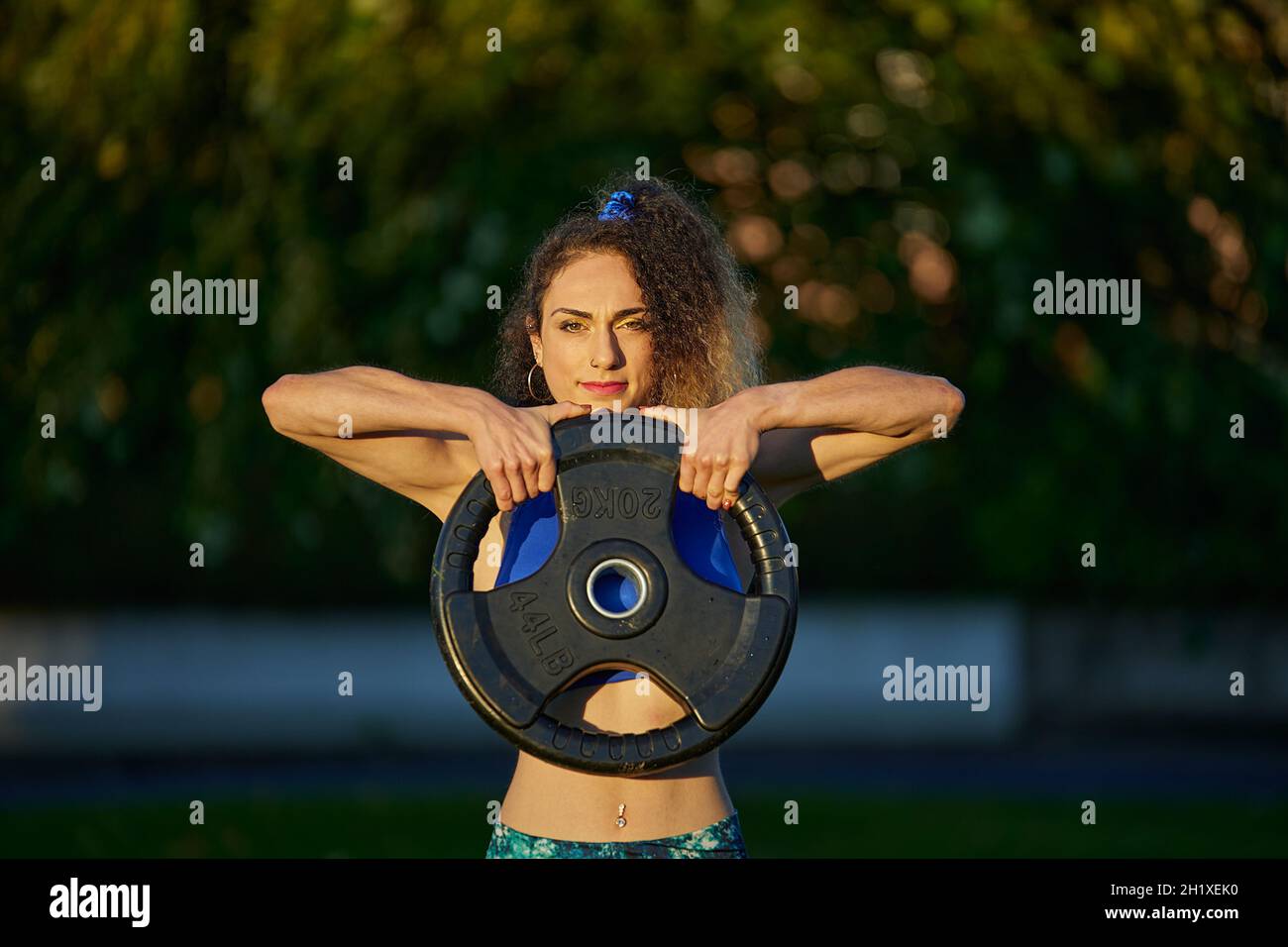 young Athletic woman throwing a heavy disc with her hands performing ...