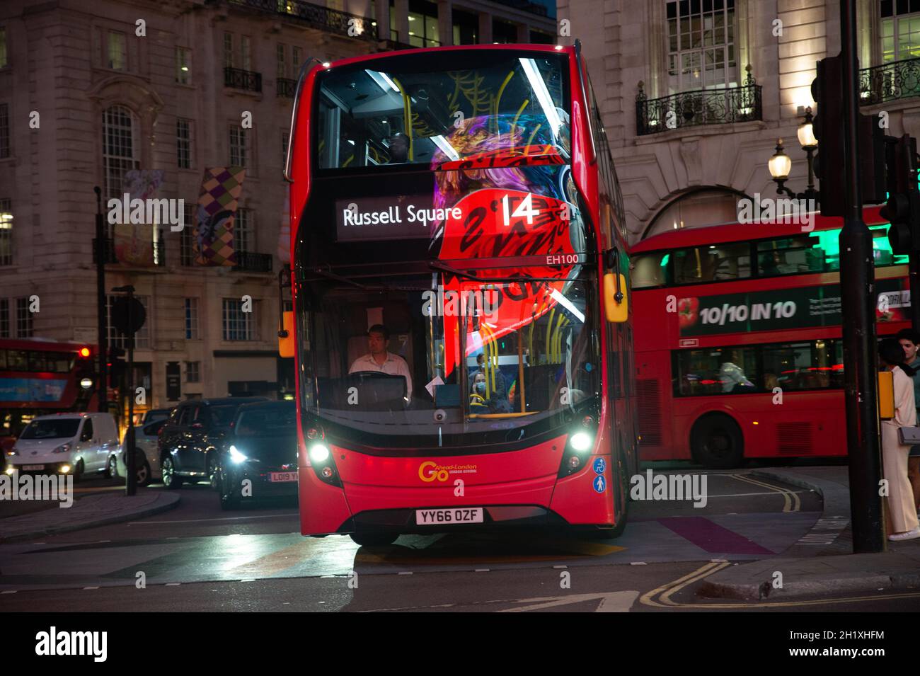 a red bus with illuminated signage reflecting on it Stock Photo - Alamy