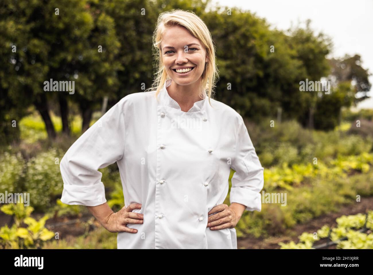 Self-sustainable female chef smiling at the camera cheerfully in an ...