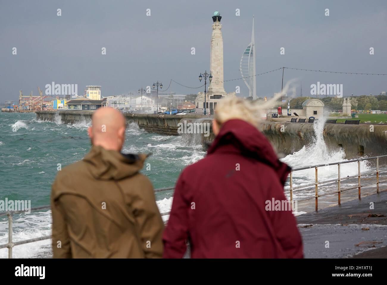 People walk along the sea front as waves crash against the sea walls in ...