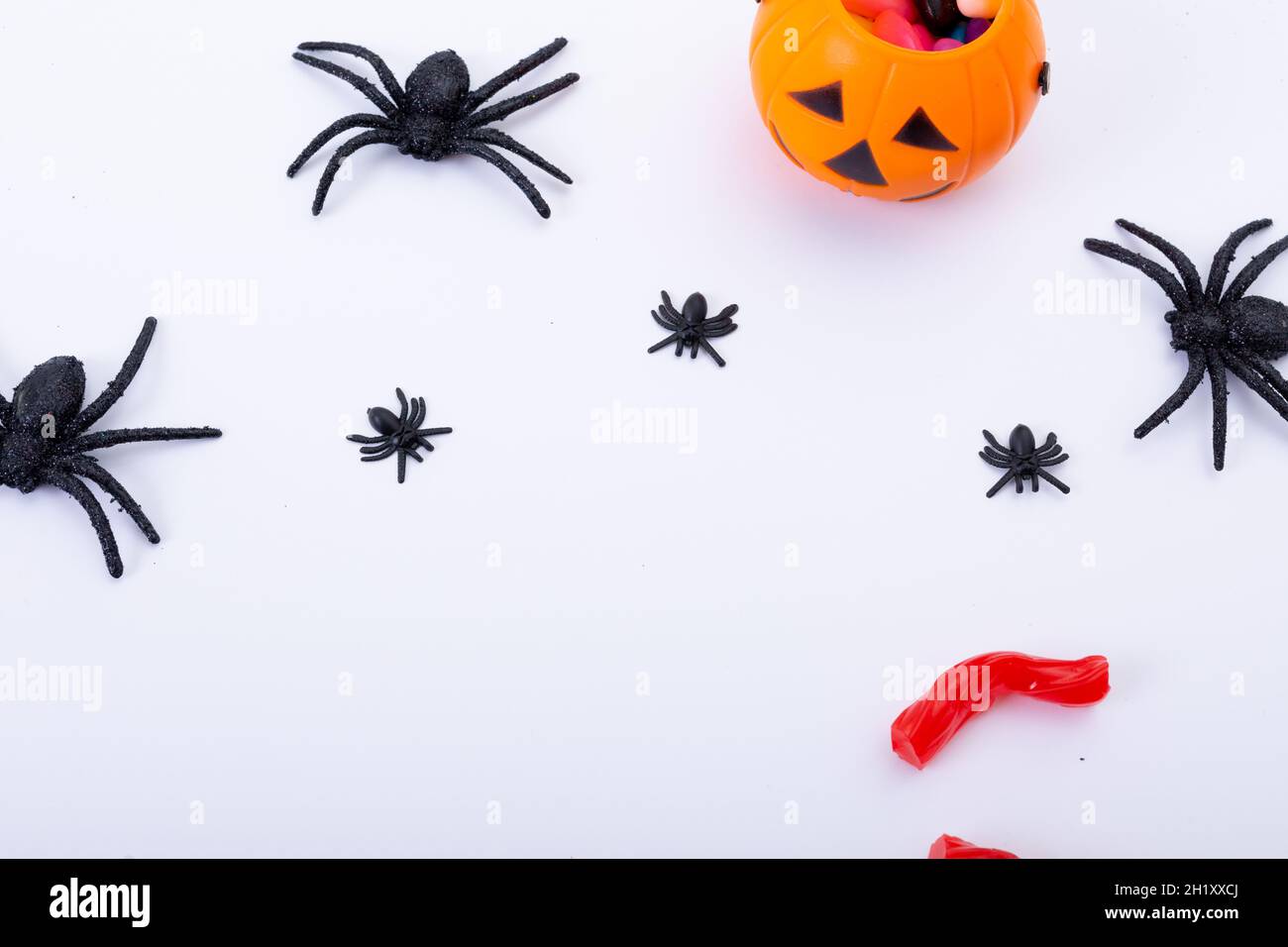 Composition of halloween spiders and pumpkin bucket with sweets with ...