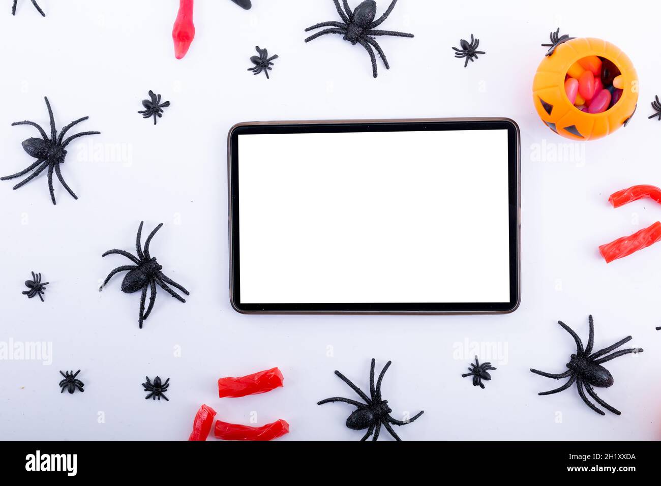 Composition of halloween spiders and sweets and tablet with copy space ...