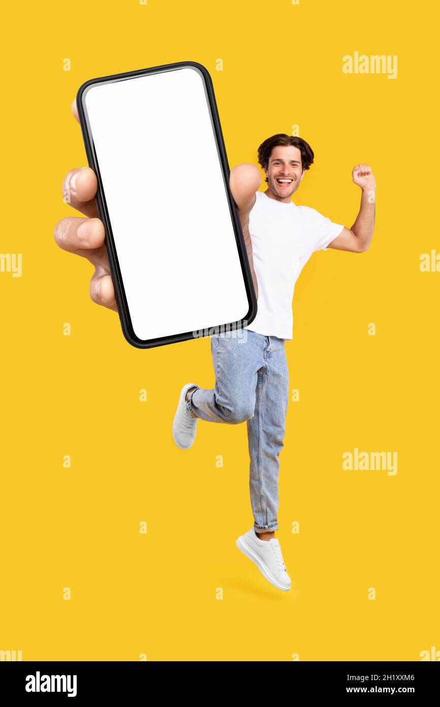Man showing white empty smartphone screen and jumping up high Stock ...