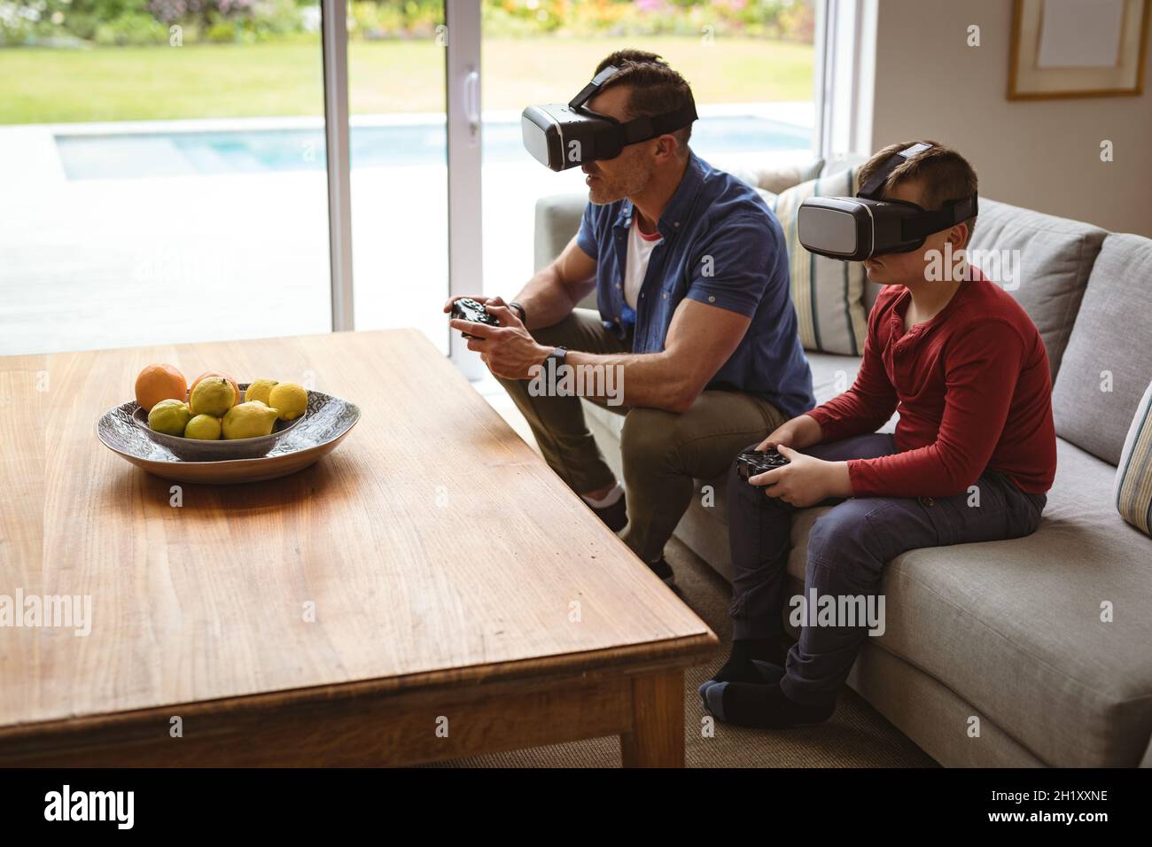 Caucasian father and son wearing vr headsets playing video games ...