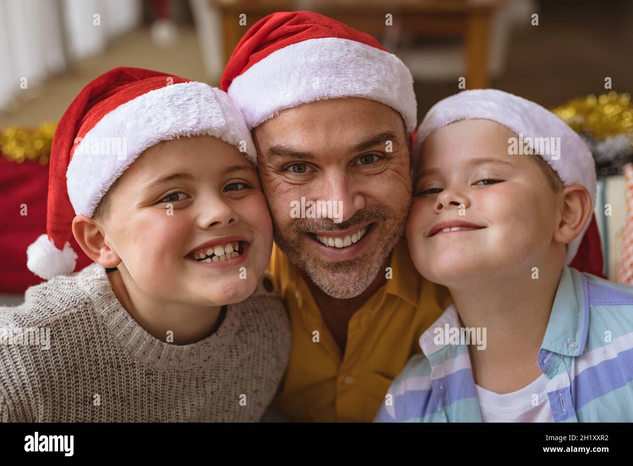 Portrait of caucasian father and two sons wearing santa hat smiling at ...