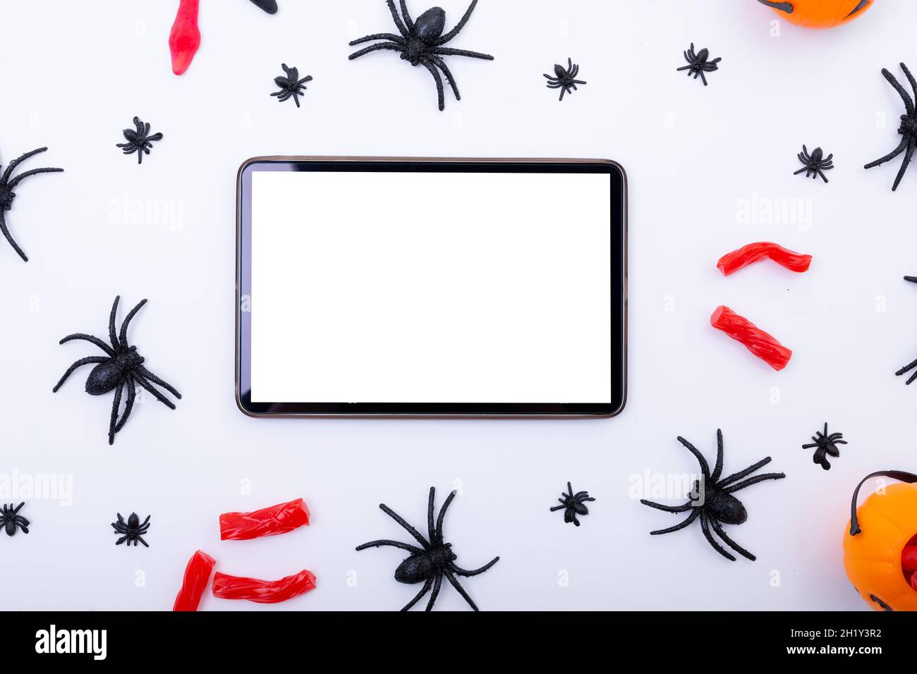 Composition of halloween spiders and sweets and tablet with copy space ...
