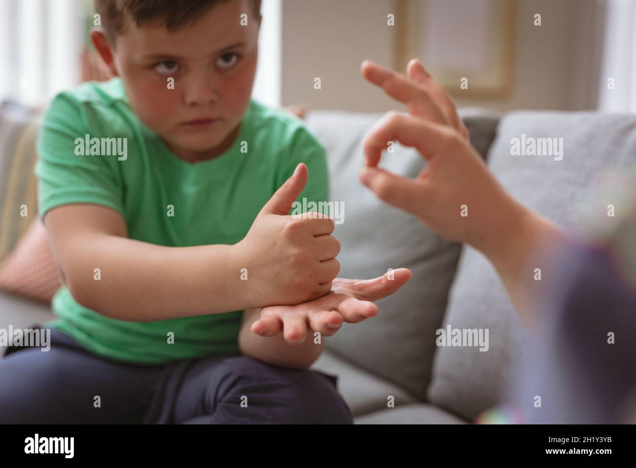 Two caucasian boys communicating using sign language while sitting on ...
