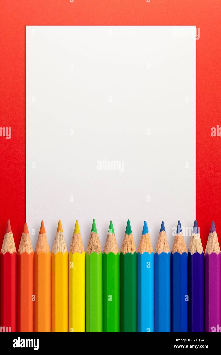 Vertical frame made of color pencils and white paper on an red ...