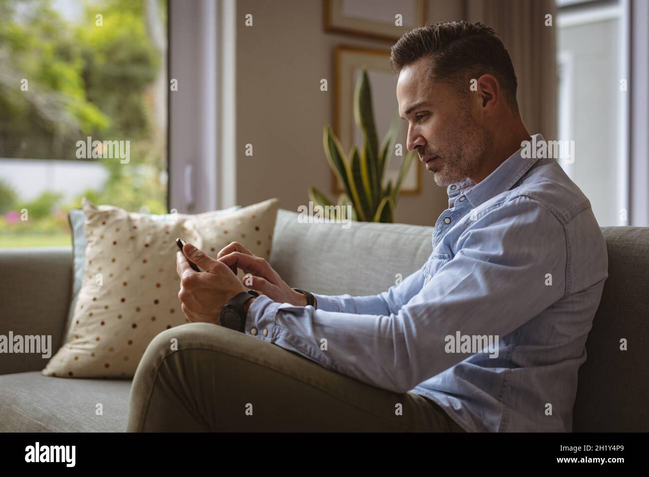 Man sitting on couch home hi-res stock photography and images - Alamy