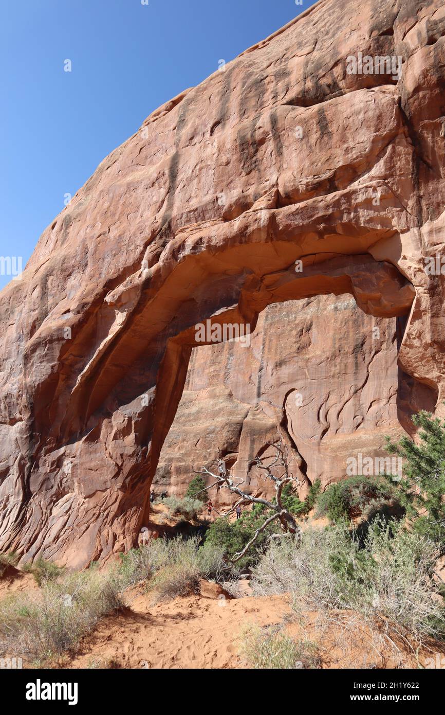 Eerie view of a large arch among rugged red rock landscape in Arches ...