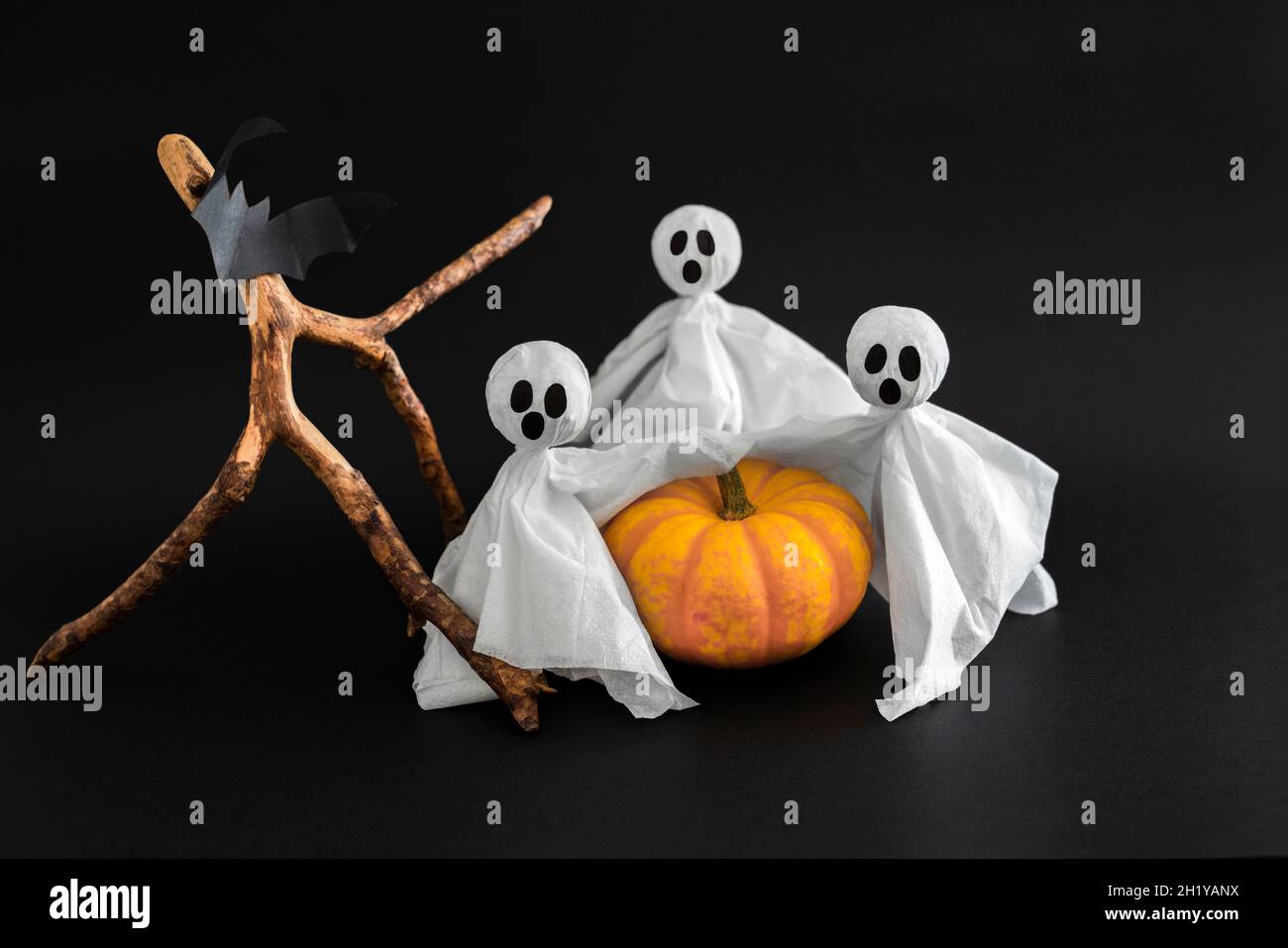 Three ghosts, bat and pumpkin on black background. Symbols of Halloween ...